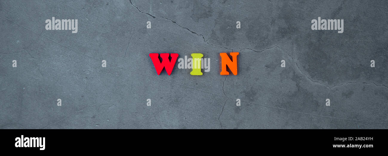 The multicolored win word is made of wooden letters on a grey plastered ...