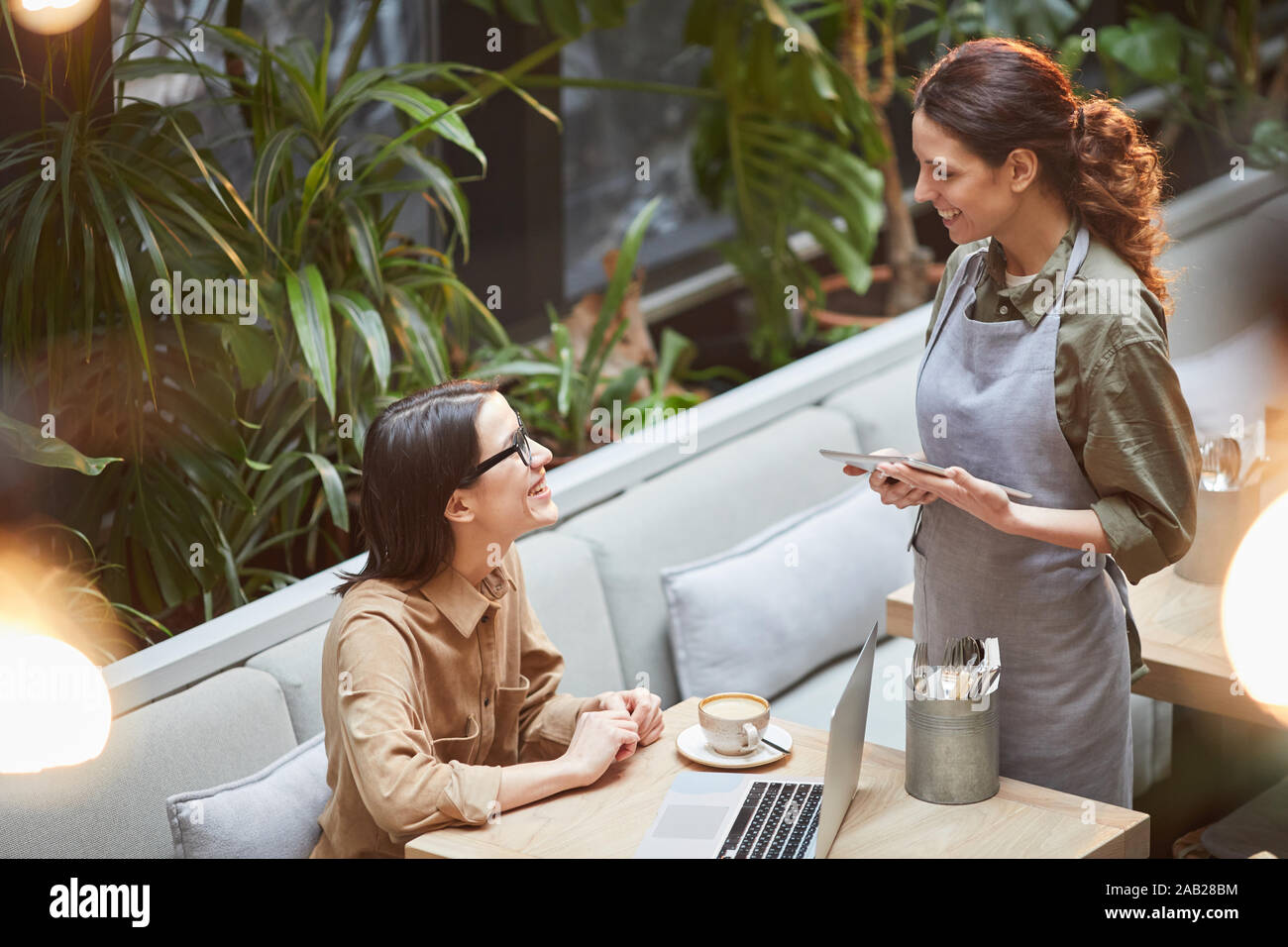 High angle portrait of smiling young waitress holding digital tablet ...