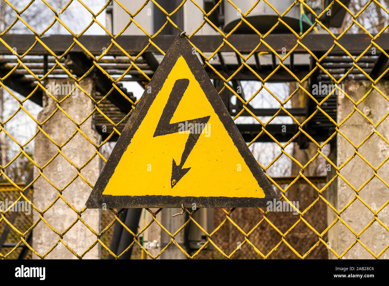 Yellow warning sign on fence of electricity substation Stock Photo - Alamy