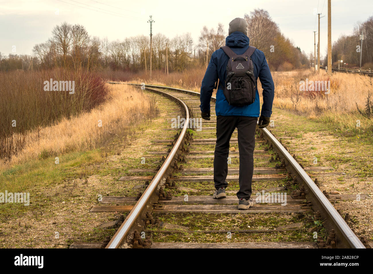 Man moves along railway tracks in the countryside. Rear view Stock ...