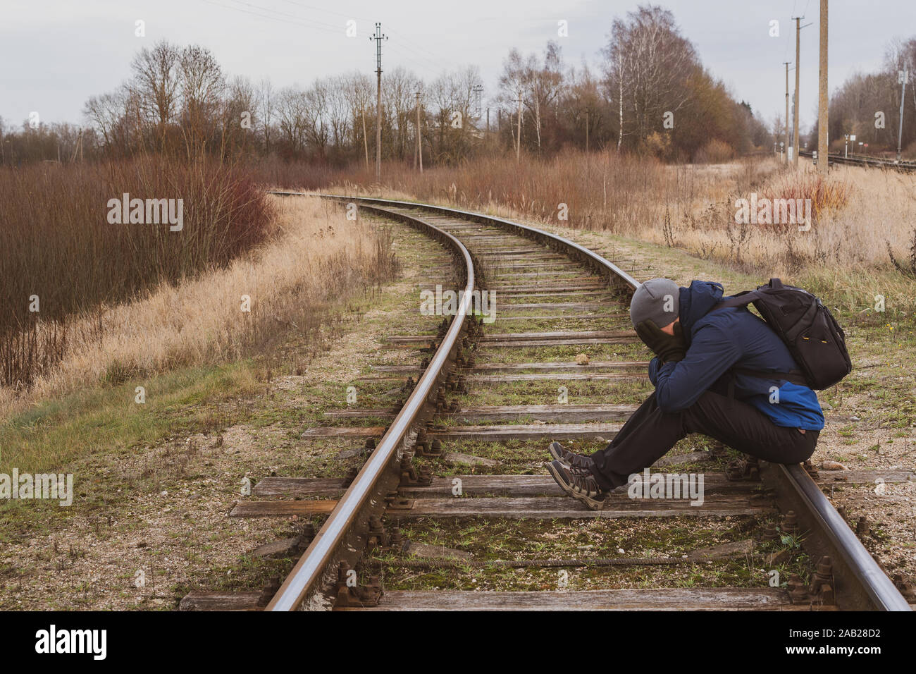 Man sitting alone on the railroad and close the face with a hands ...