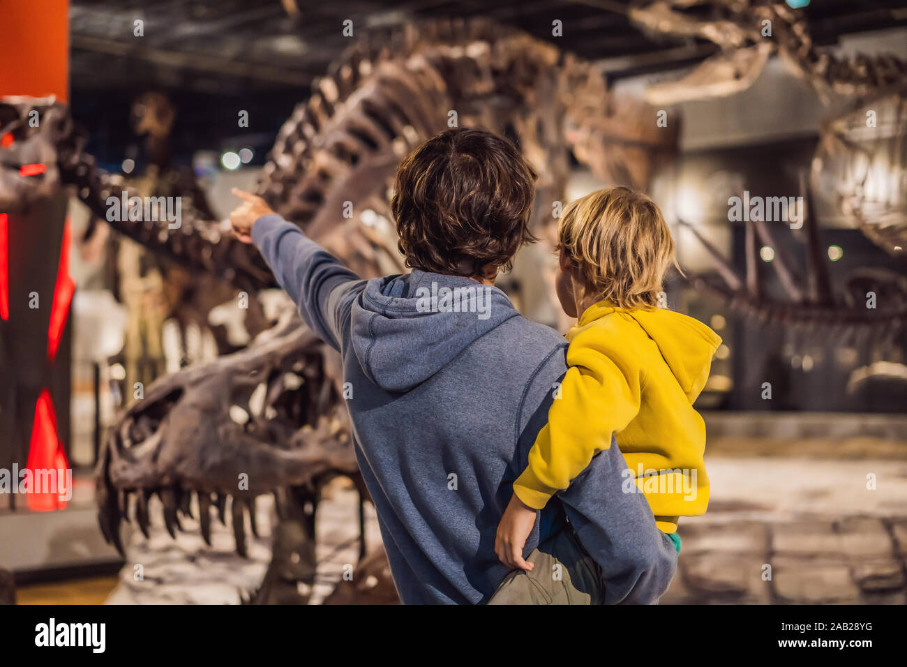 Dad and boy watching dinosaur skeleton in museum Stock Photo - Alamy