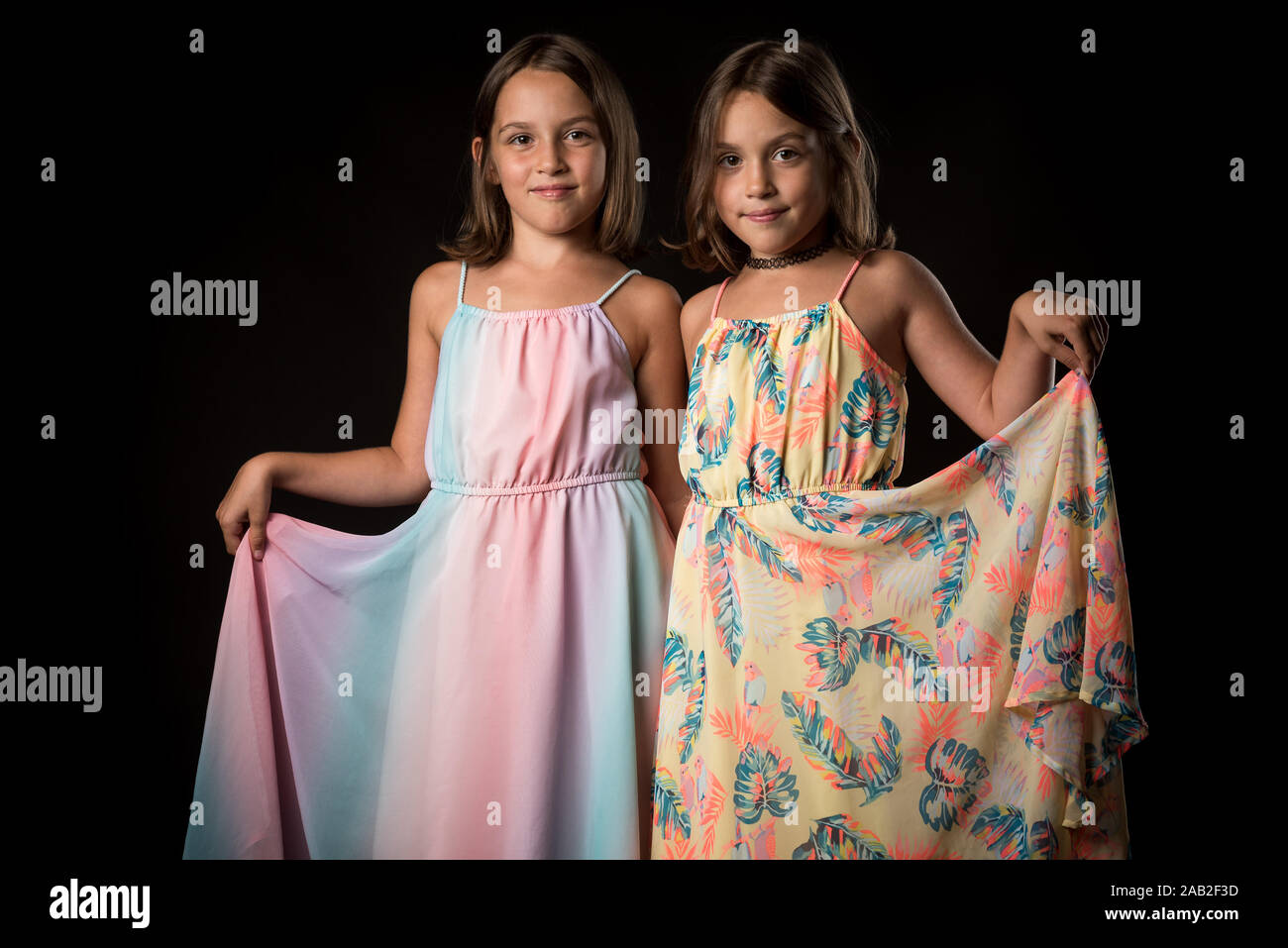 Identical twin girls sisters are posing for the camera. Happy twin ...