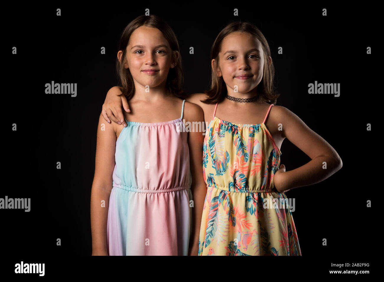 Identical twin girls sisters are posing for the camera. Happy twin ...