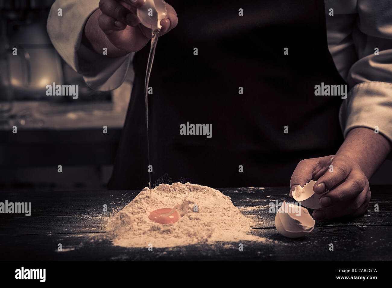 The chef breaks eggs into a flour on a wooden table Stock Photo - Alamy