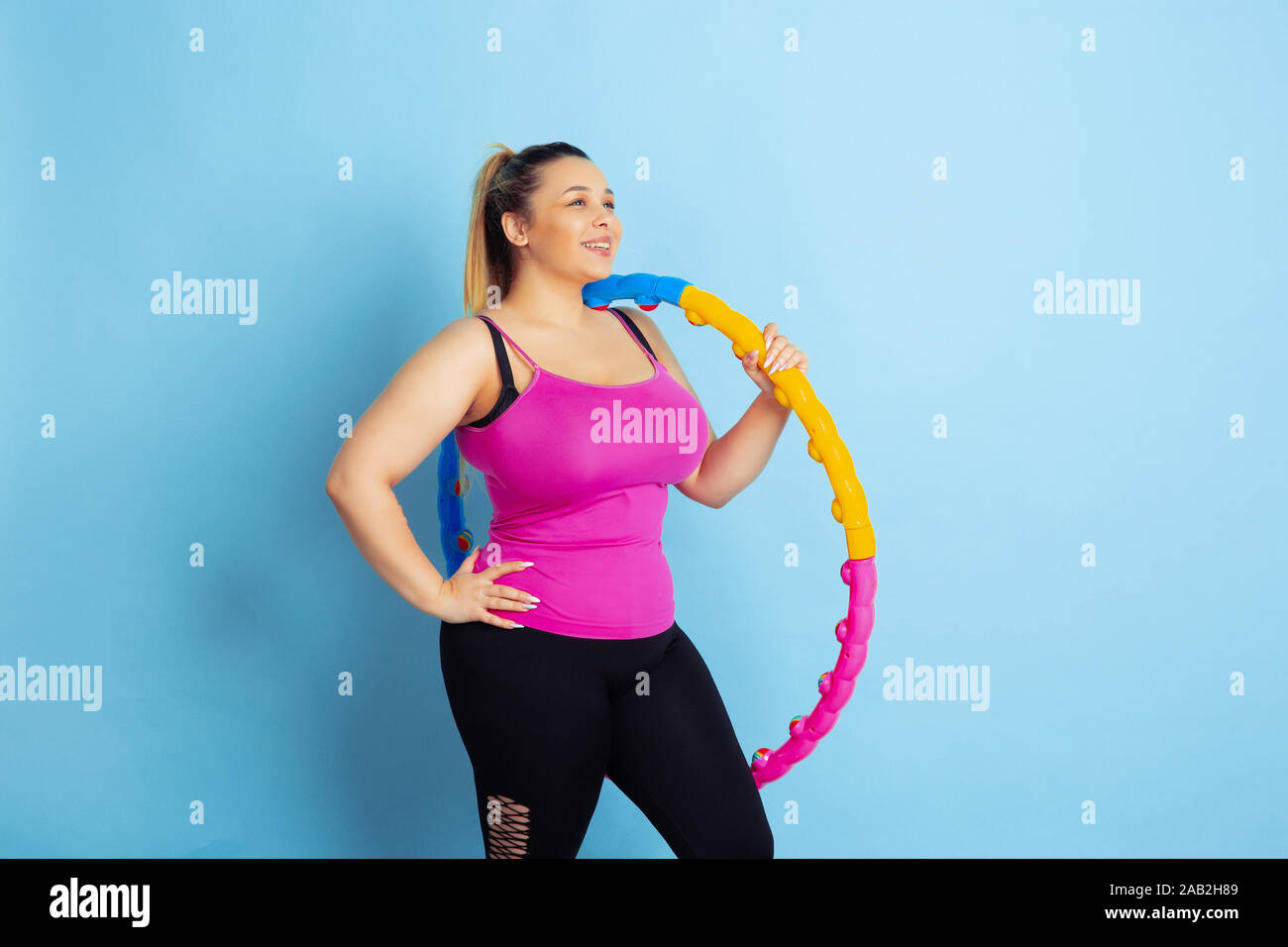 Young caucasian plus size female model's training on blue background ...