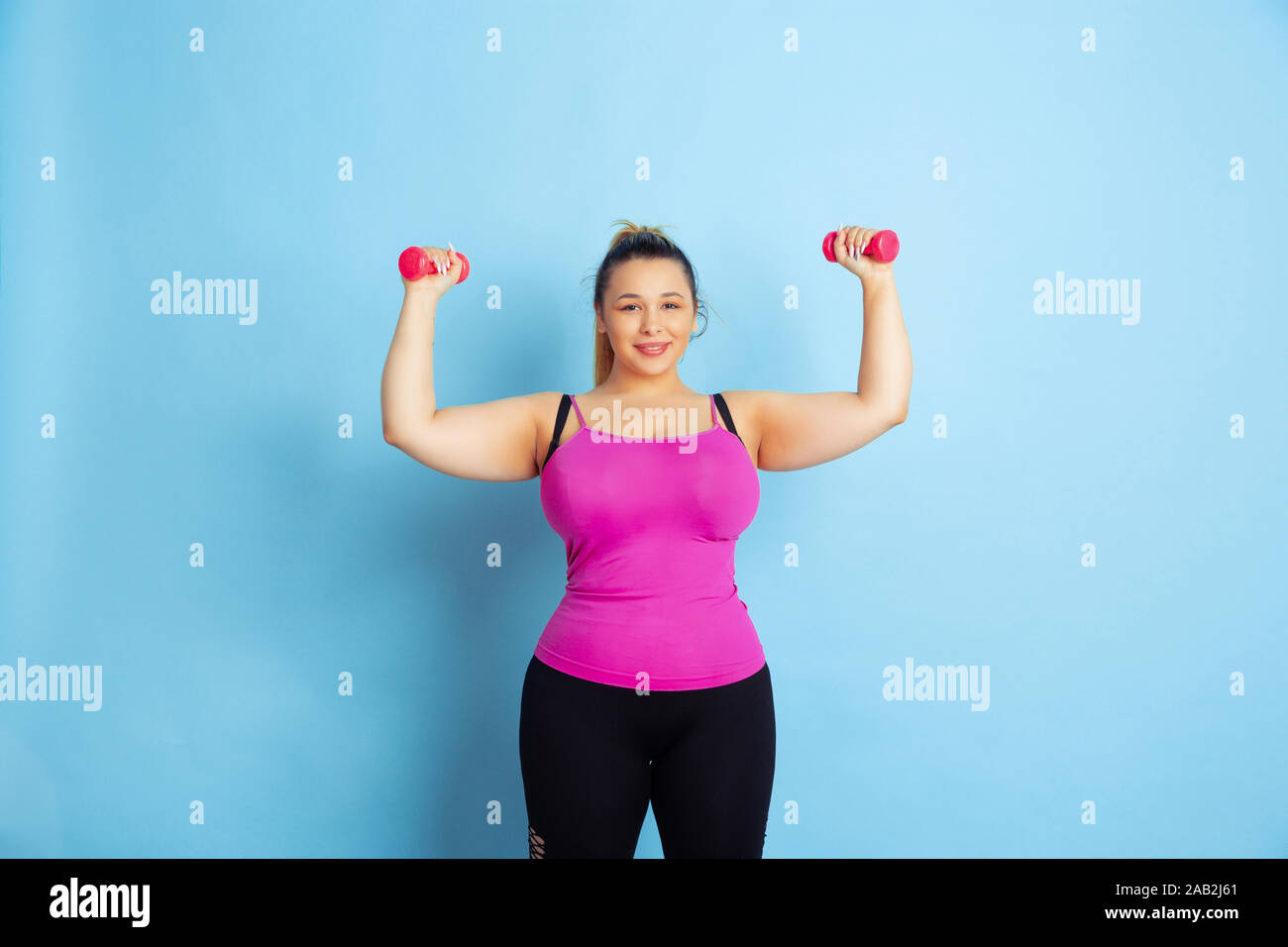 Young caucasian plus size female model's training on blue background ...