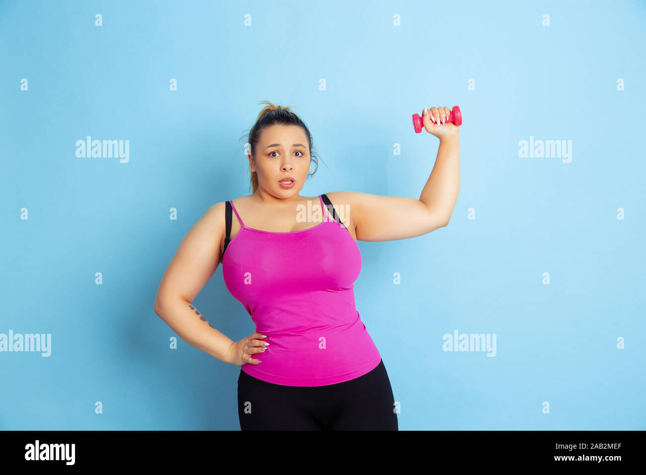 Young caucasian plus size female model's training on blue background ...