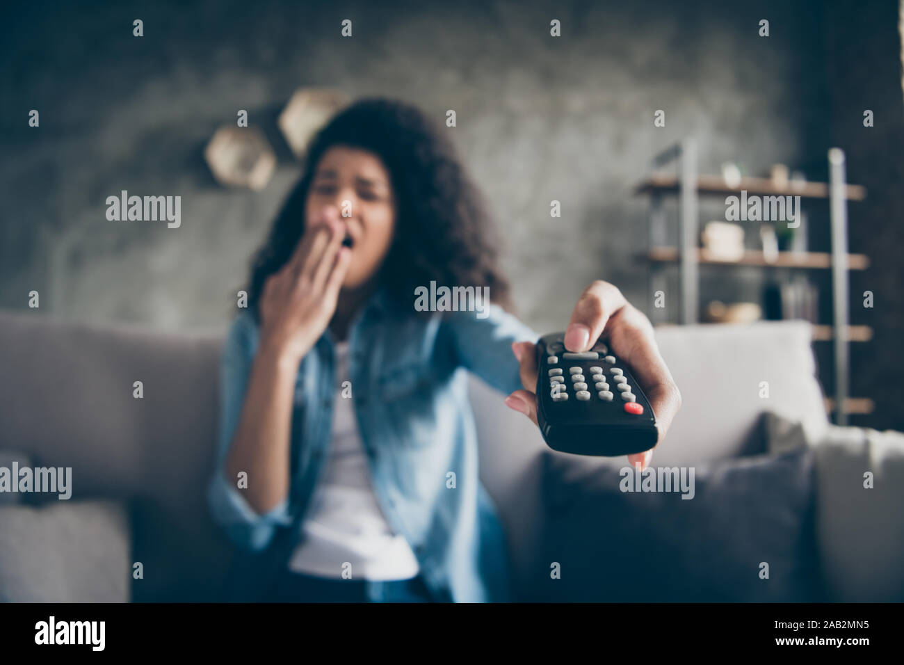 Photo of dark skin wavy lady homey mood holding tv remote control ...