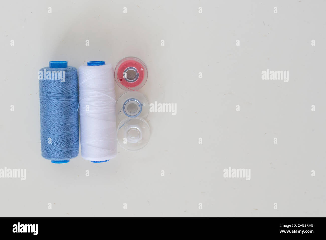 Colored bobbins and spools of thread for machine sewing on a light ...
