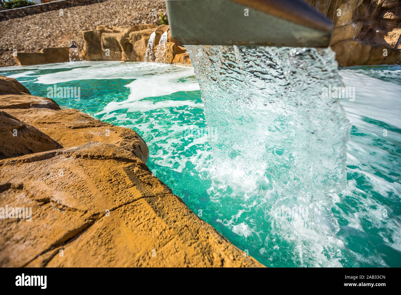 Stream water out of artificial waterfall in outdoor pool Stock Photo ...