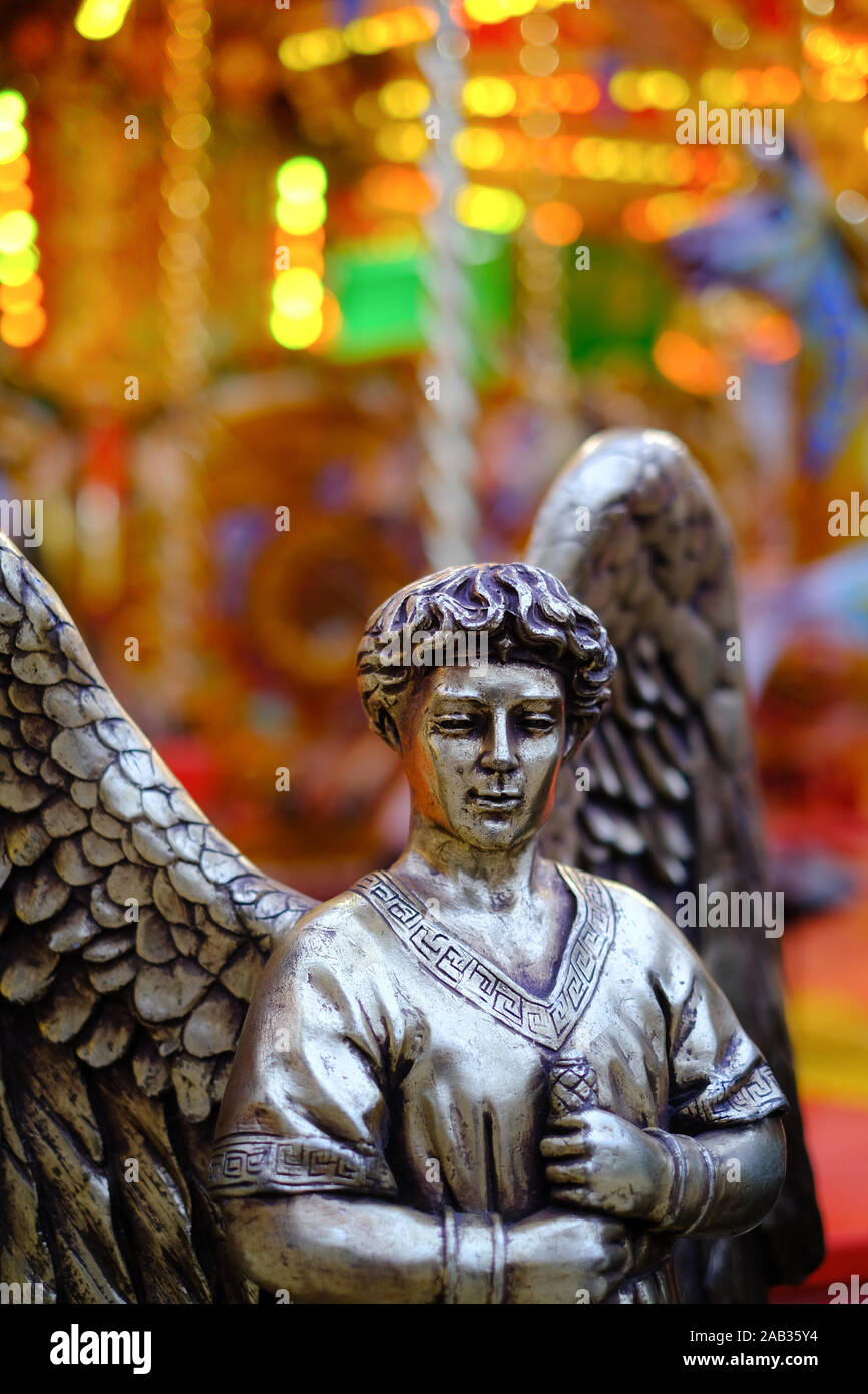 An angel stands guard in front of a traditional carousel ride at ...