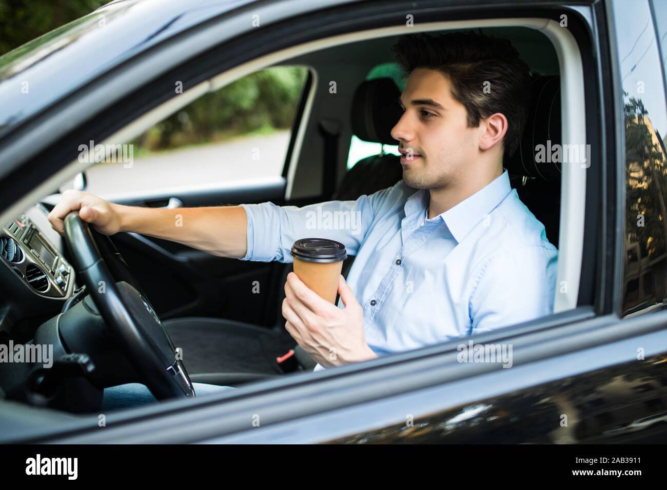 transportation and vehicle concept - man drinking coffee while driving ...