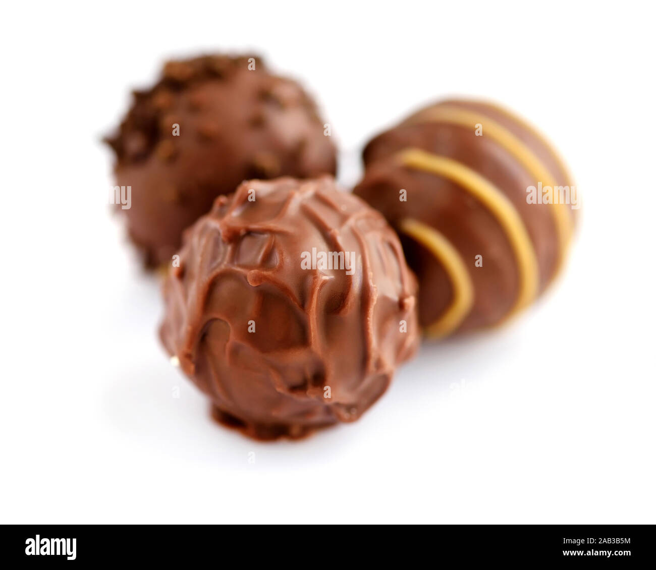 Three candies of milk chocolate on white background. Selective focus ...