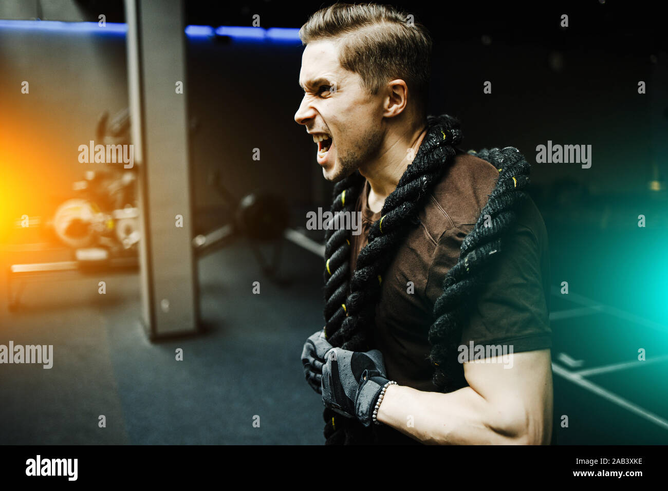 Athletic man pulling rope in dark sports hall. Sunlight effect Stock ...