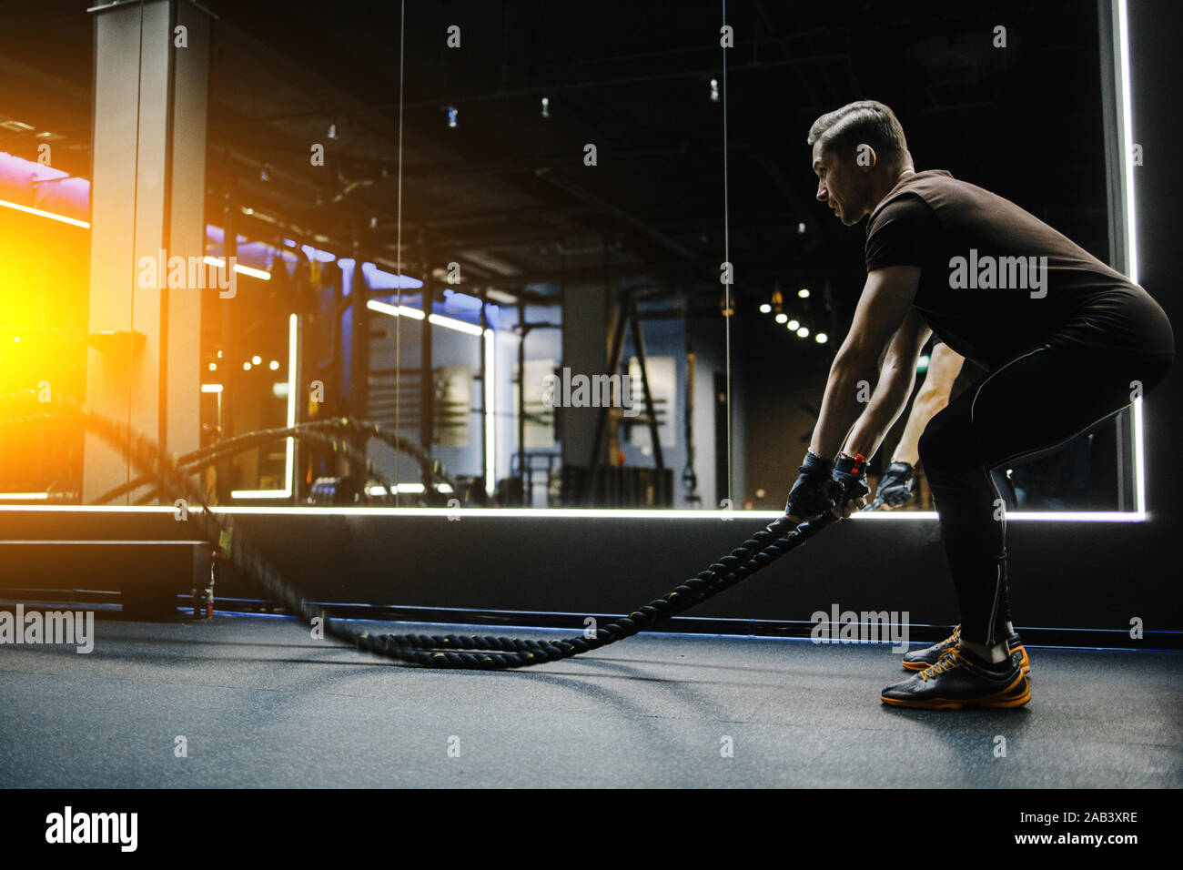 Sportsman pulling rope in dark sports hall. Sunlight effect Stock Photo ...