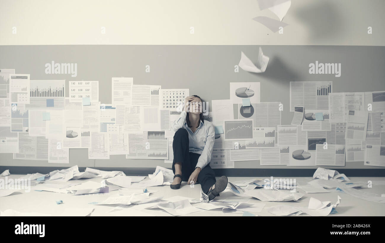 Exhausted confused businesswoman sitting on the floor surrounded by ...