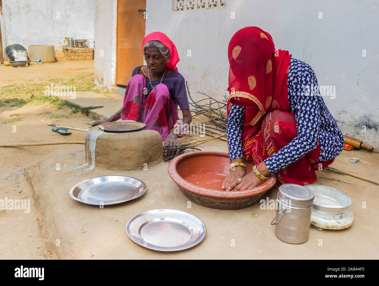 Two women making chapati bread outside their home in a village in ...