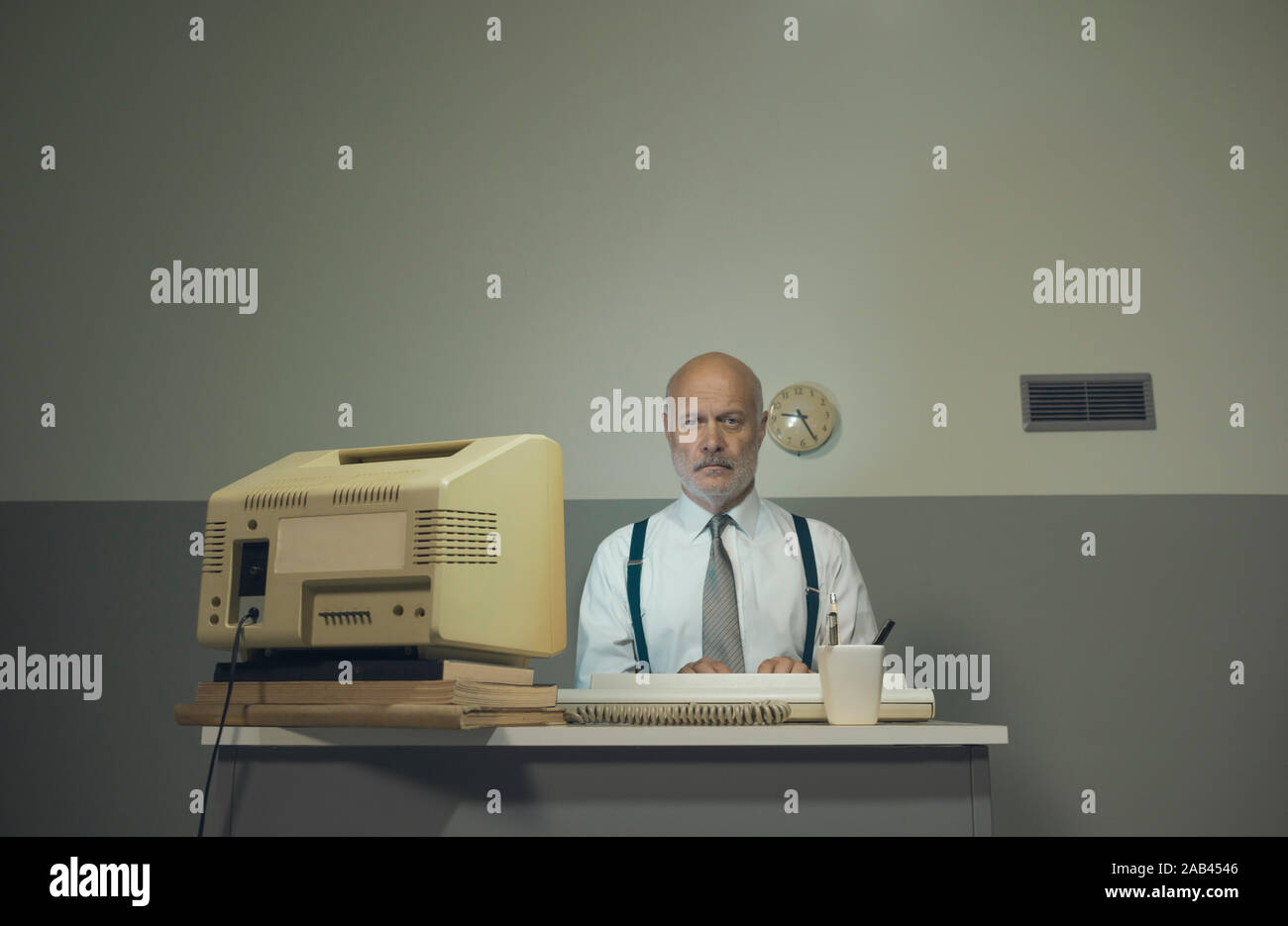 Sad senior businessman working with an outdated computer on a small ...