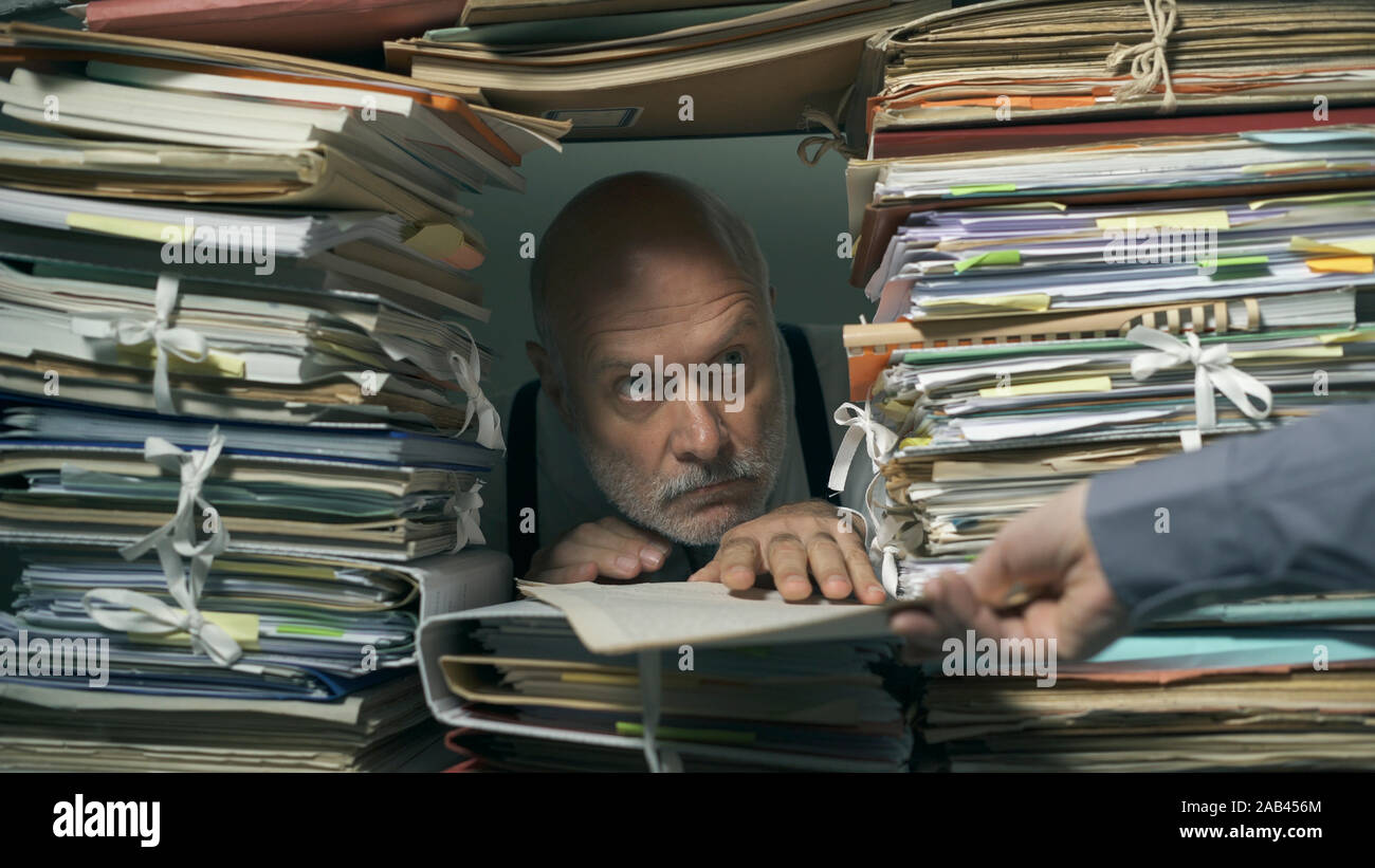 Creepy office clerk overloaded with paperwork, he is peeking out from a ...