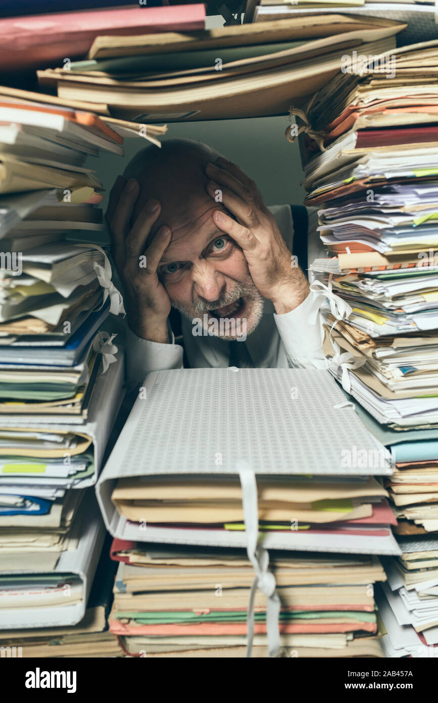 Panicked stressed businessman overwhelmed with paperwork, taxes and ...