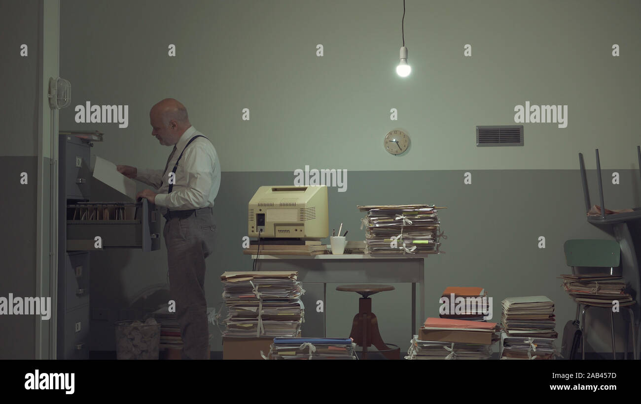 Corporate businessman searching for files in a rundown messy office ...