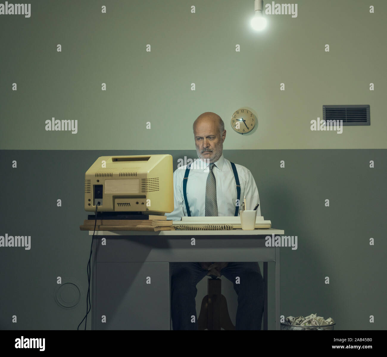 Sad senior businessman working with an outdated computer on a small ...