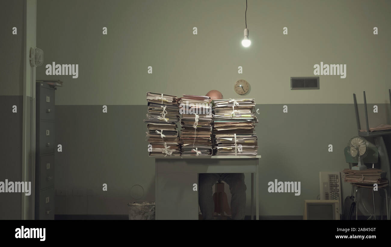 Businessman working behind a lot of stacked paperwork on his desk in a ...