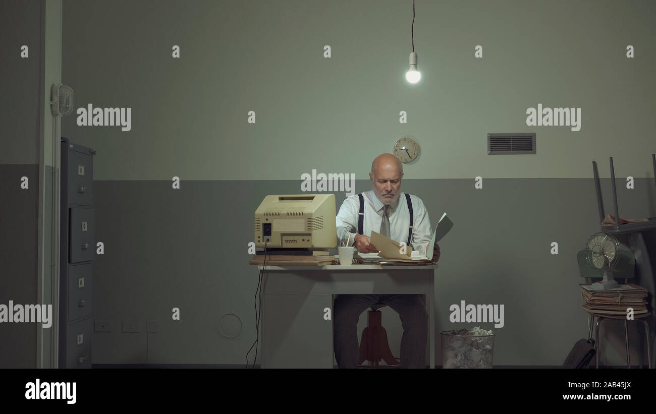 Sad vintage style businessman working in a small rundown office with an ...