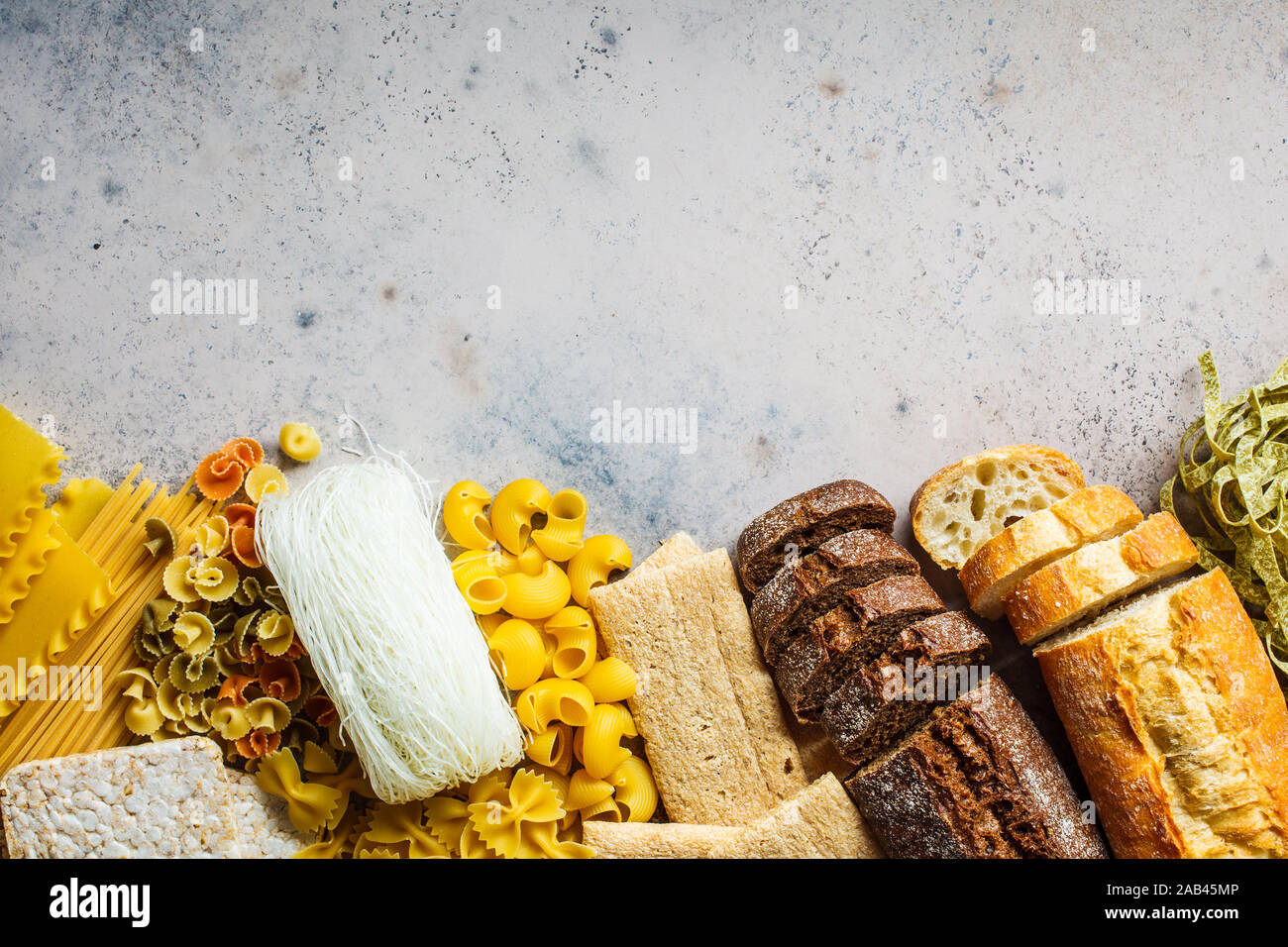 Various pasta background. Bread and different types of pasta on a gray ...