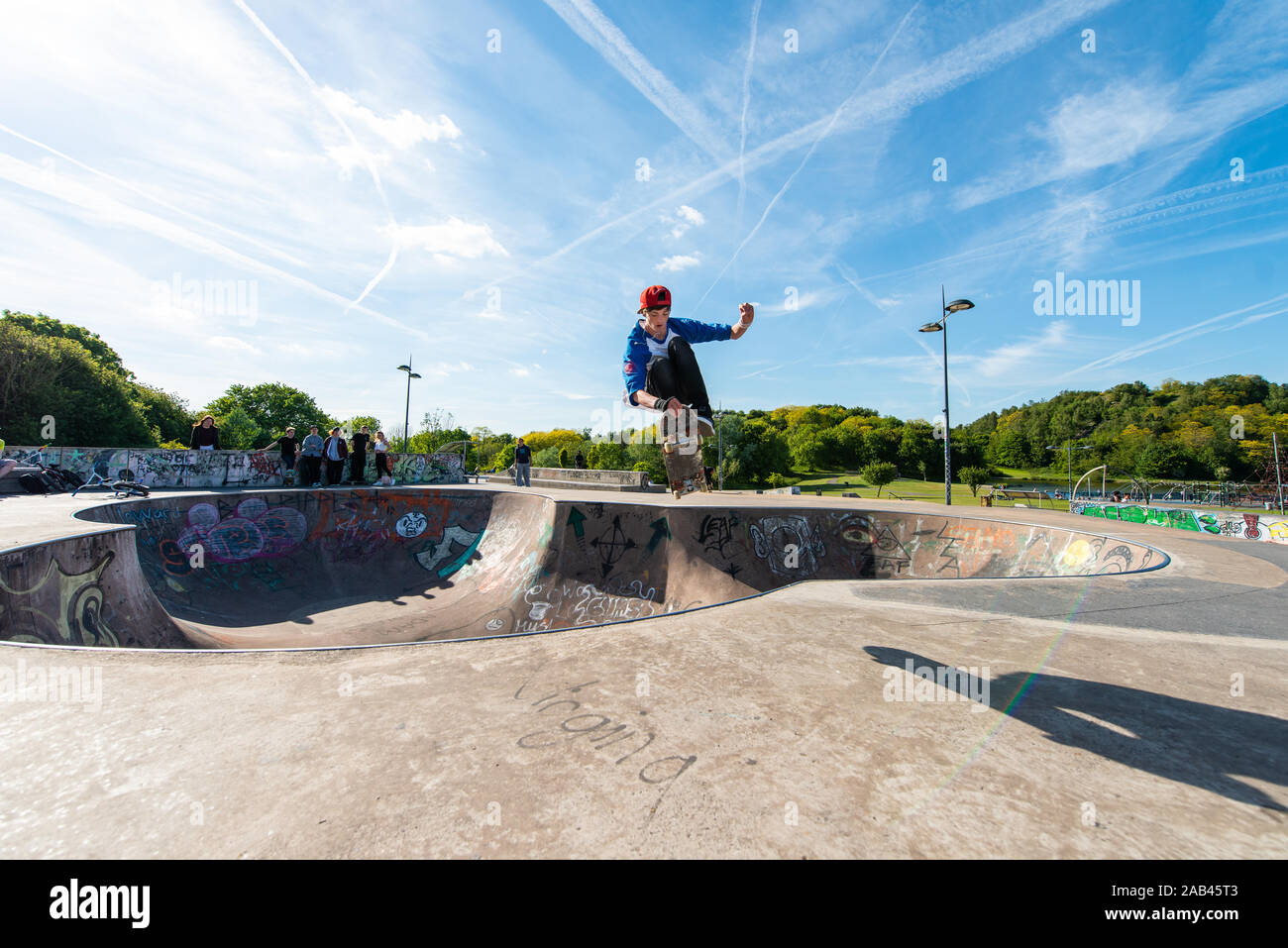 Professional skateboarders skating out of a concrete bowl and doing a ...