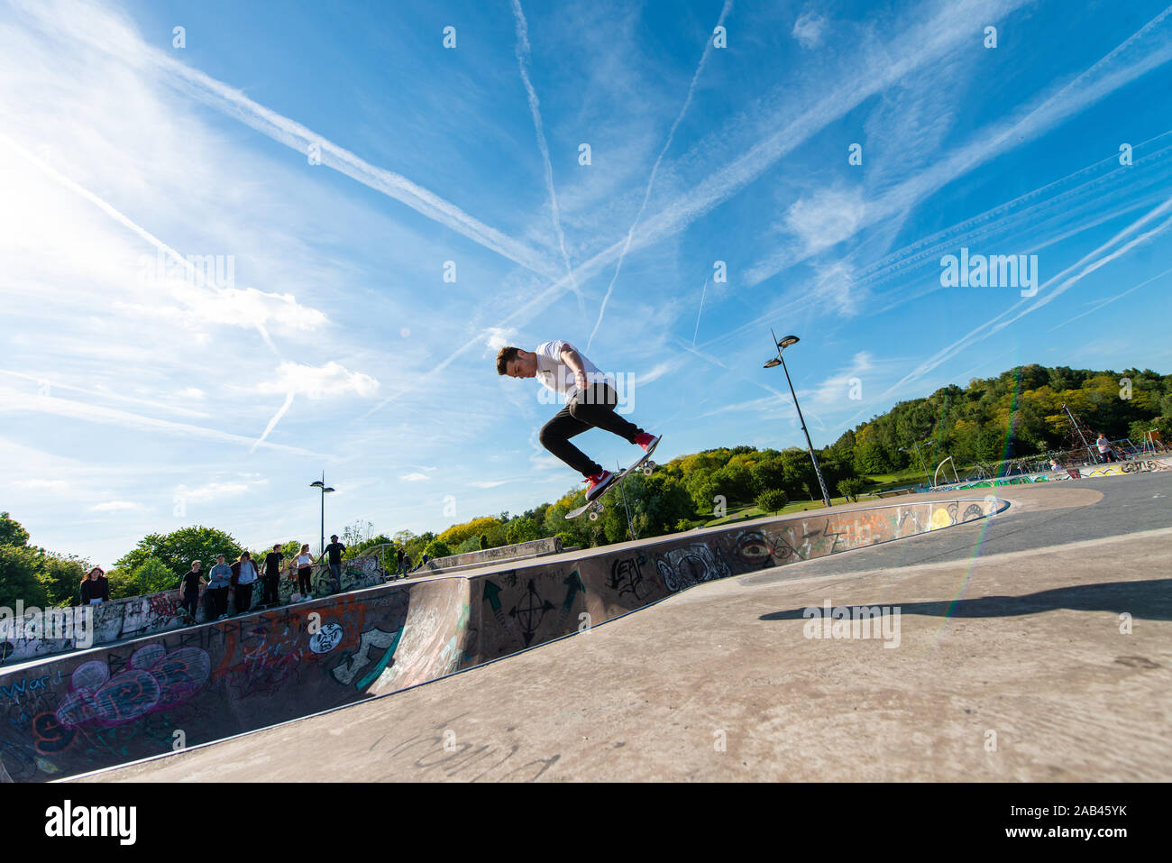 Professional skateboarders skating out of a concrete bowl and doing a ...