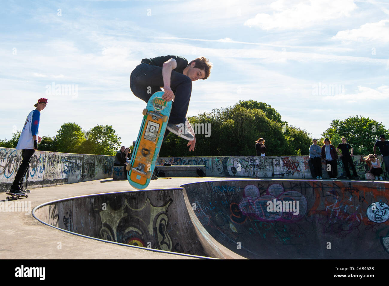 Professional skateboarders skating out of a concrete bowl and doing a ...