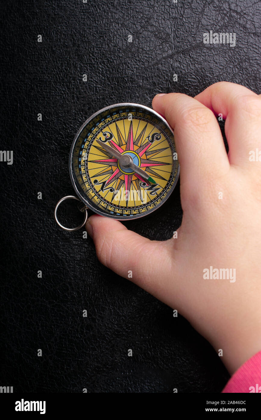 Hand is holding a magnetic compass on black background Stock Photo - Alamy