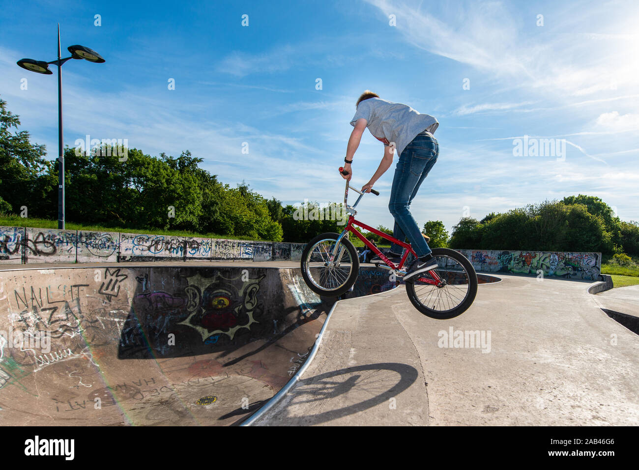 A young kid at the local skatepark practicing on his BMX, riding around ...