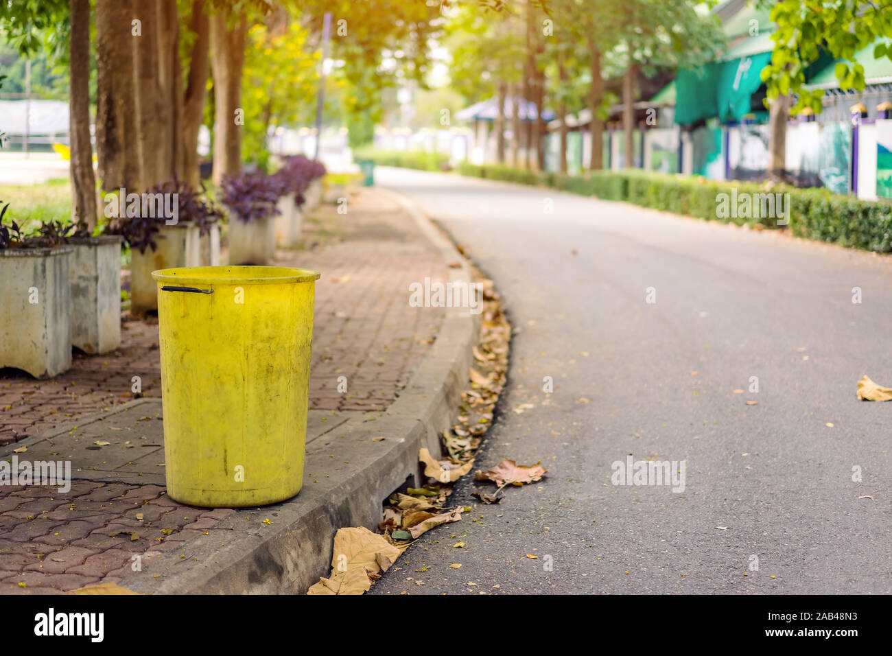 An old yellow dustbin in the public park beside the walk way for ...