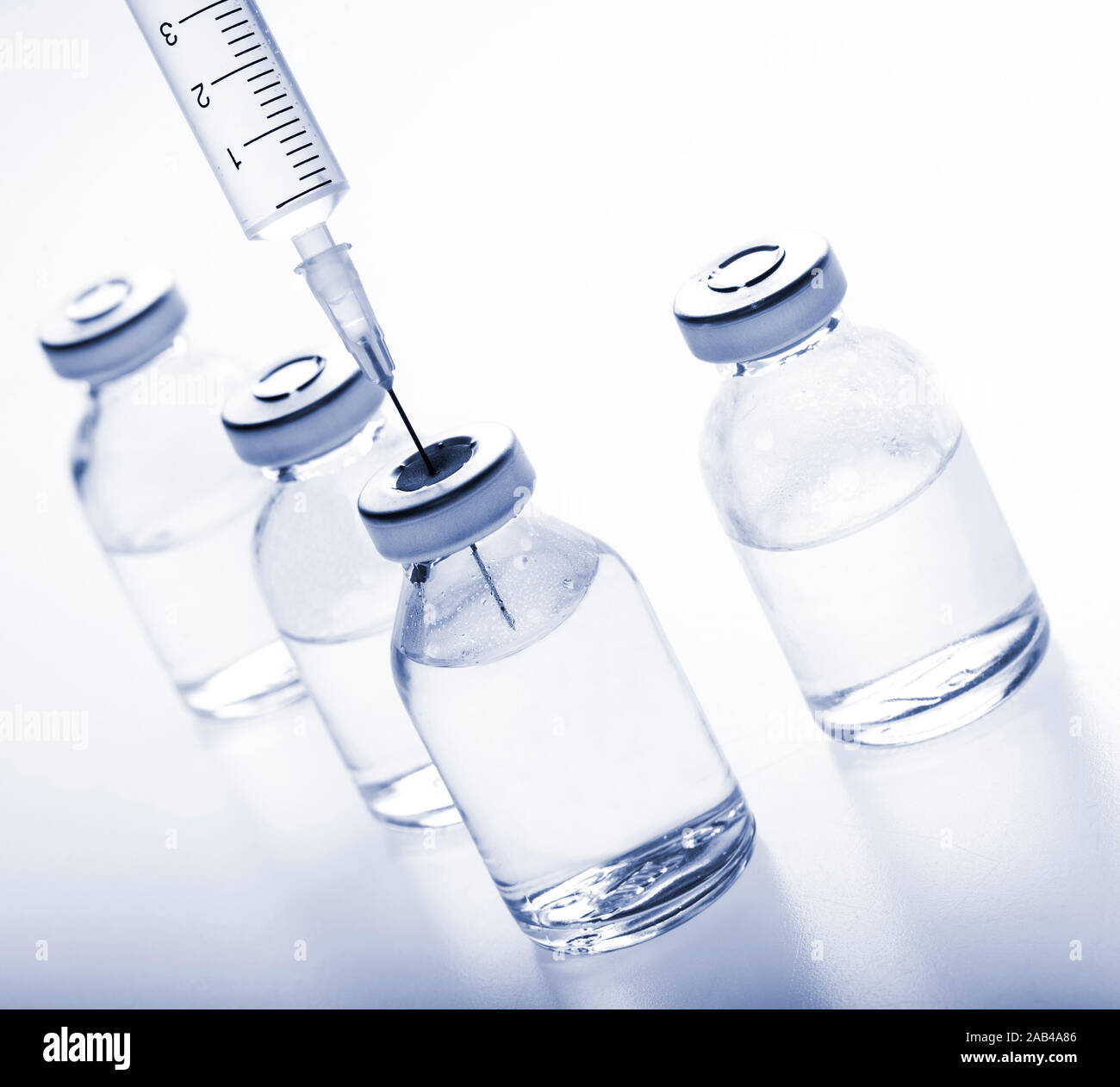 Glass medicine vials with liquid and syringe on white background. Toned ...