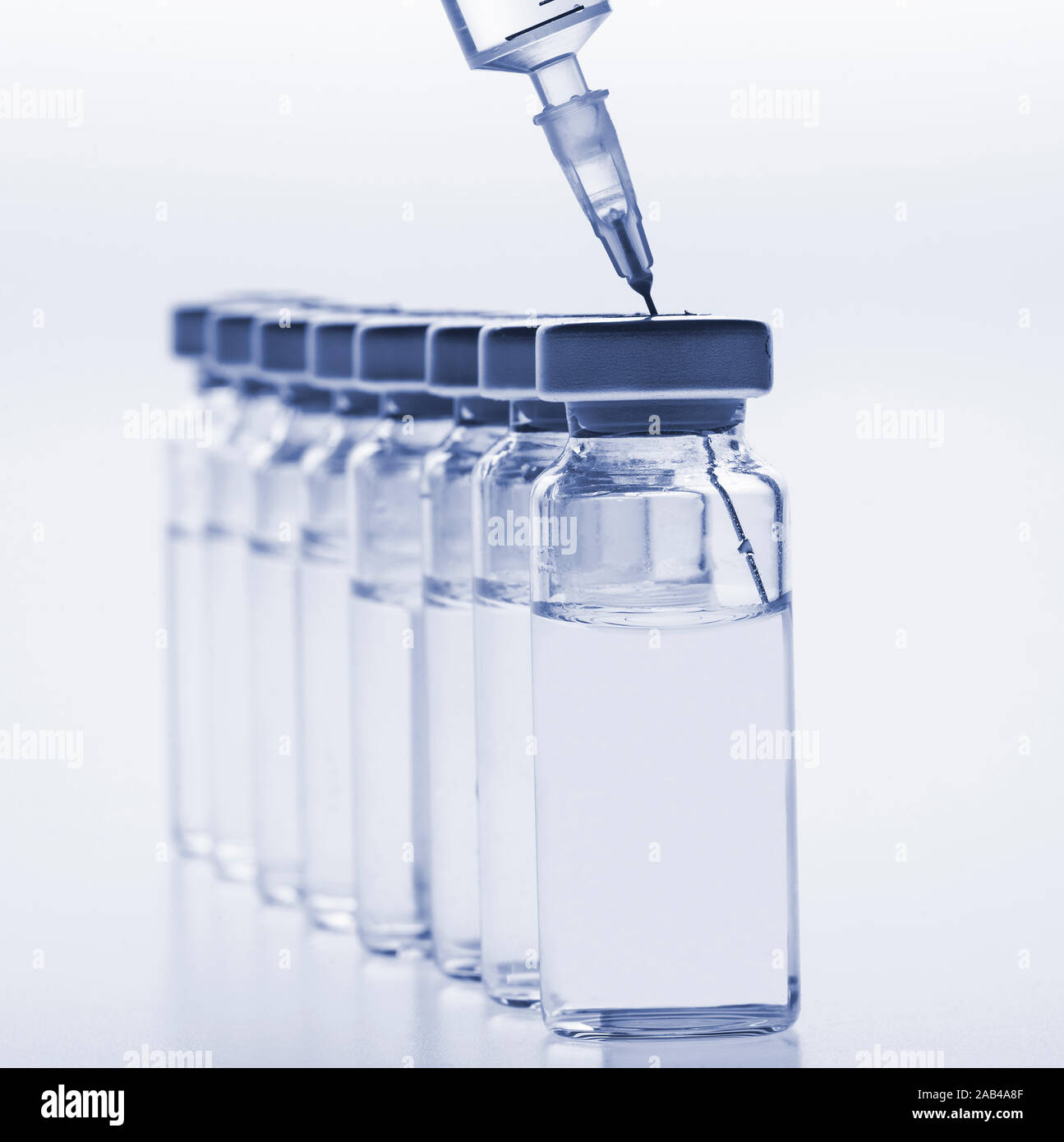Glass medicine vials with liquid and syringe on white background. Toned ...