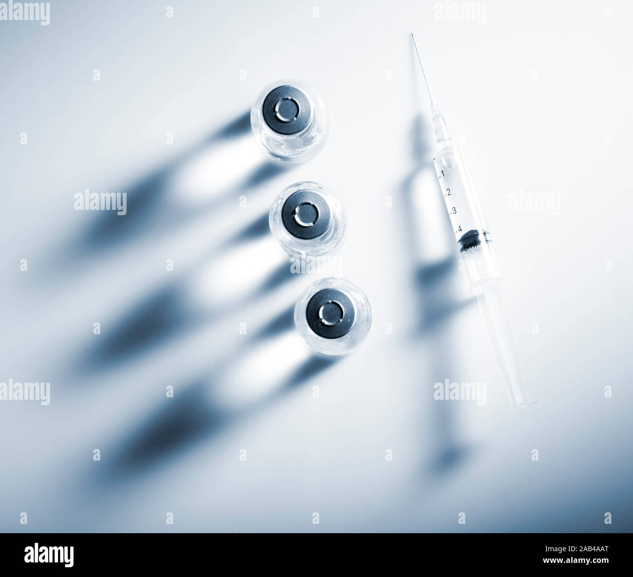 Glass medicine vials with liquid and syringe on white background. Toned ...