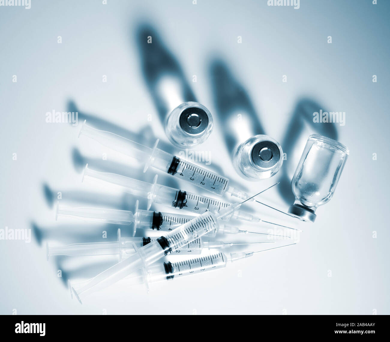 Glass medicine vials with liquid and syringe on white background. Toned ...