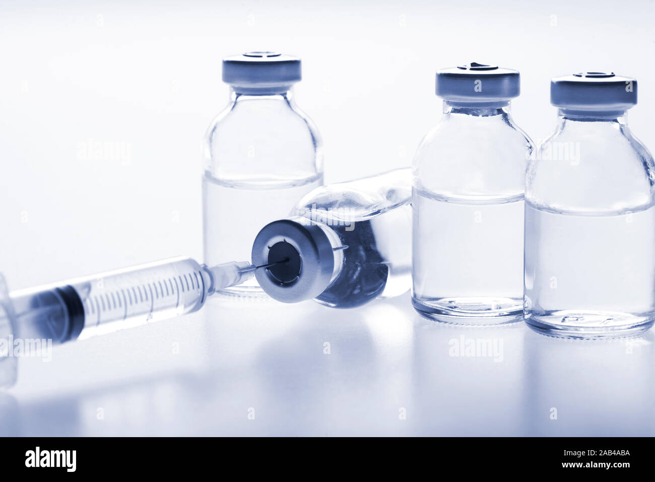 Glass medicine vials with liquid and syringe on white background. Toned ...