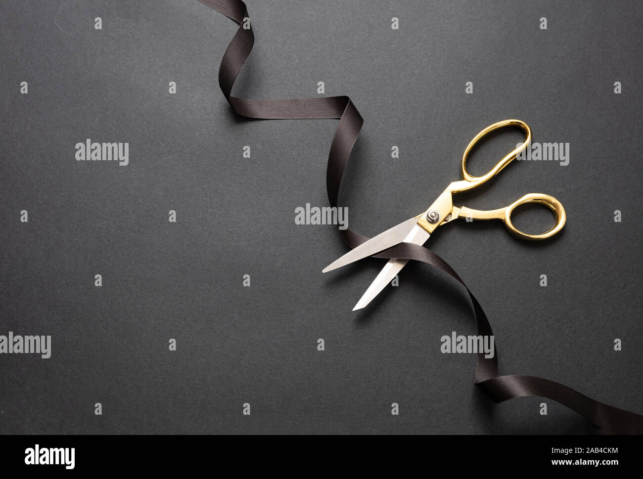 Grand opening. Gold scissors cutting black silk ribbon, black ...