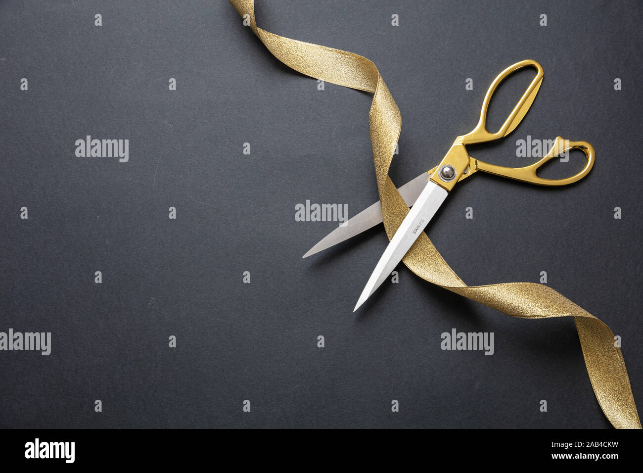 Grand opening. Gold scissors cutting gold silk ribbon, black background ...