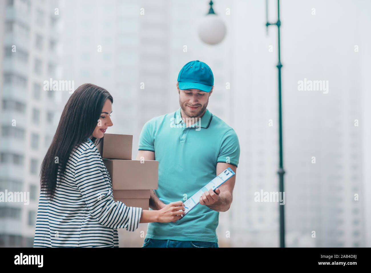 Delivery man wearing cap giving declaration to customer Stock Photo - Alamy