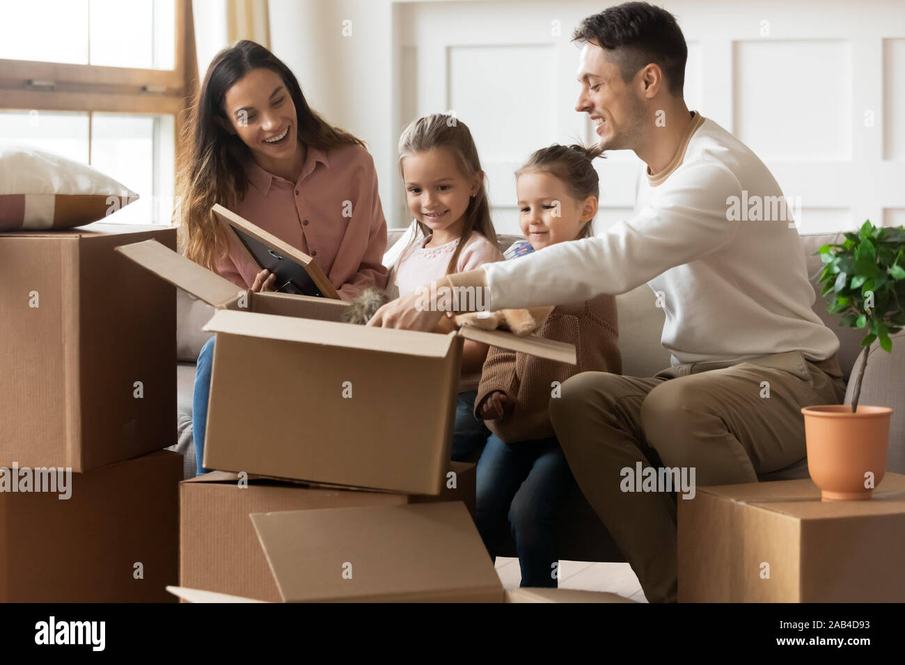 Happy family with children unpacking boxes on moving day Stock Photo ...
