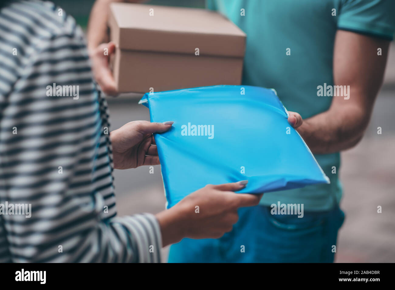 Woman taking her parcel while meeting delivery man Stock Photo - Alamy