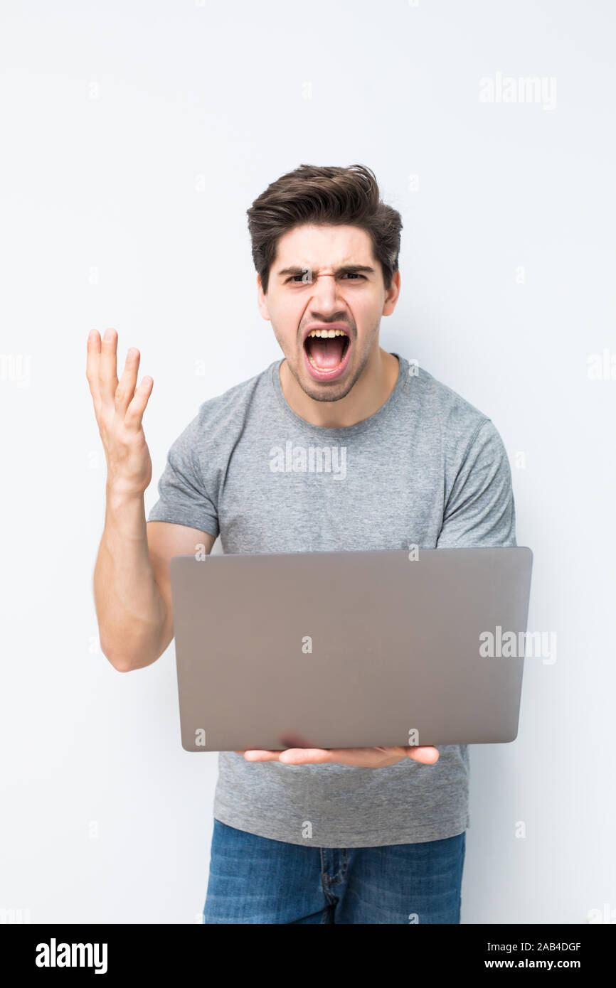 Angry upset man holding laptop and screaming over white background ...