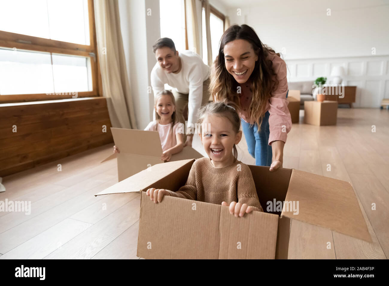 Happy parents playing with little kids riding in box Stock Photo - Alamy