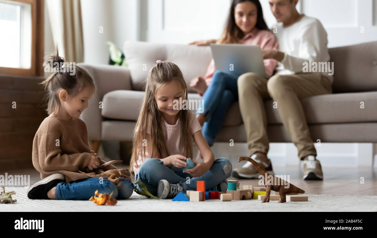 Happy kids playing while parents using laptop in living room Stock ...