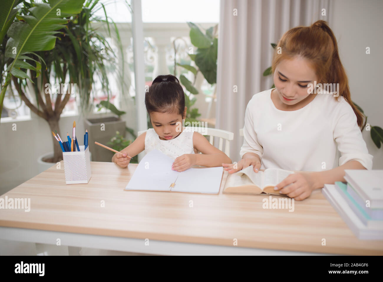 mother and daughter learning to write, mother teaching little girl ...